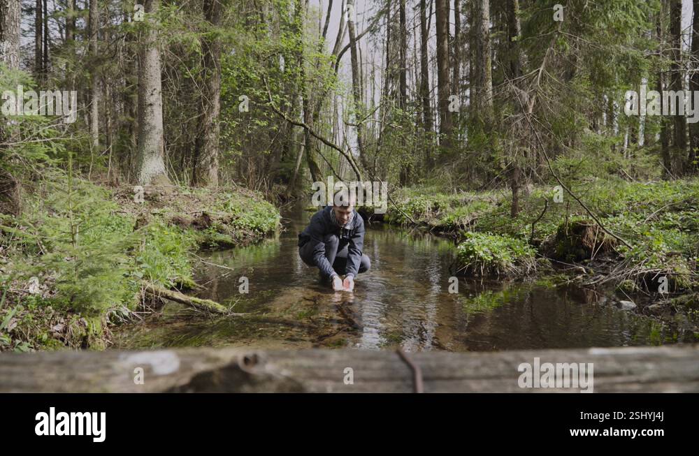 Thin man washes face with pure cold water in forest creek Stock Video ...