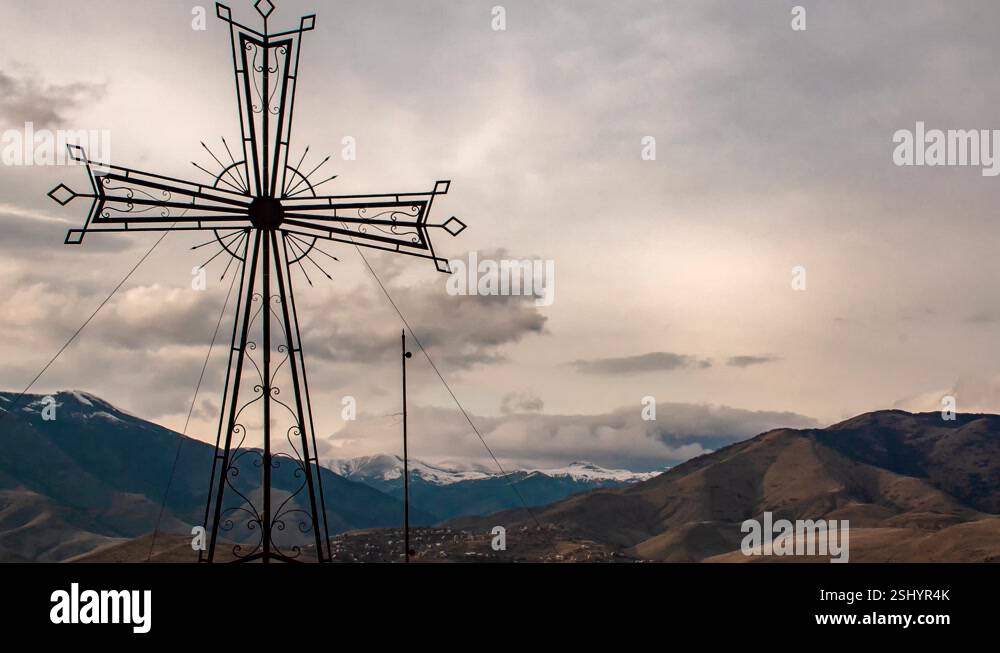 A tall metal Christian cross is erected outdoors in the mountains and ...