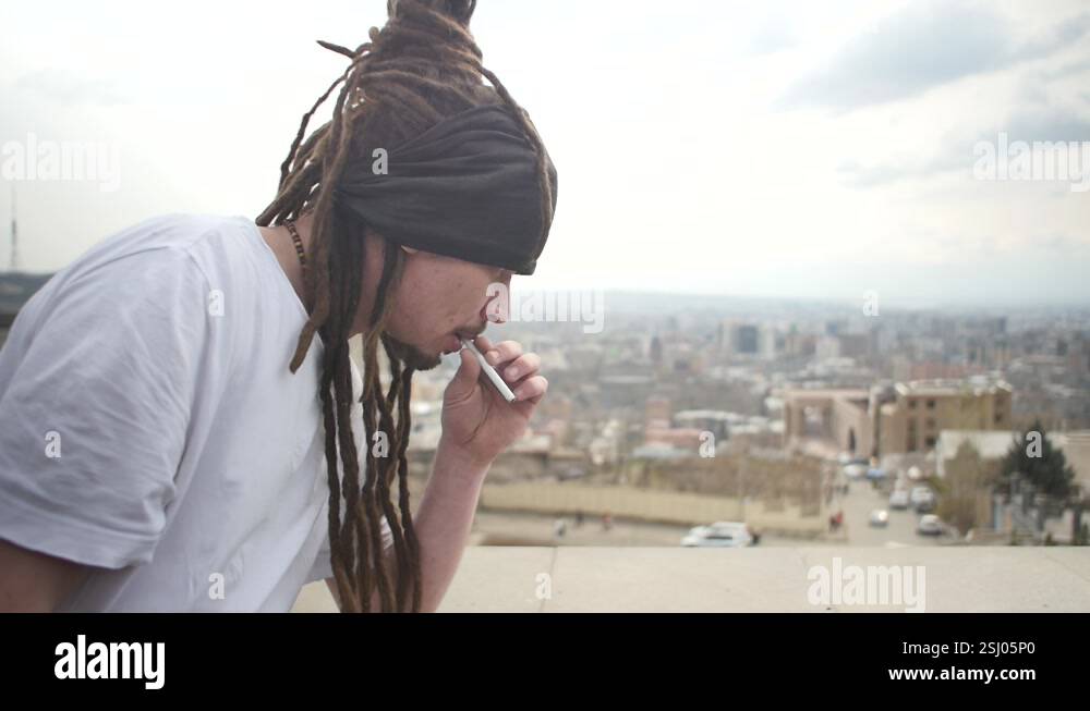 A guy with dreadlocks, beads and bracelets on his arm sets fire to a ...