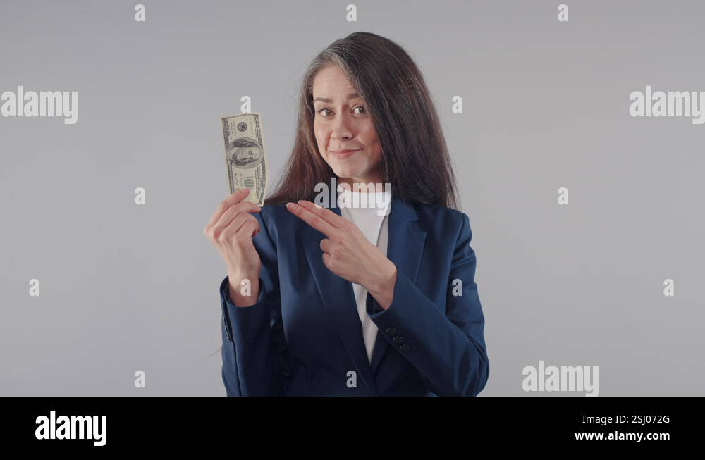 Positive business woman with hundred dollar bill in her hand studio ...