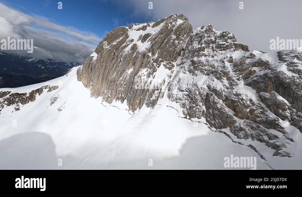 FPV sport drone raising shot to winter mountain peak cliff summit ...