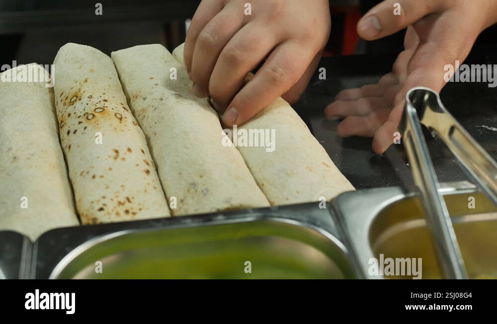 The hands of the cook takes many shawarma or doner kebabs rolled up on ...
