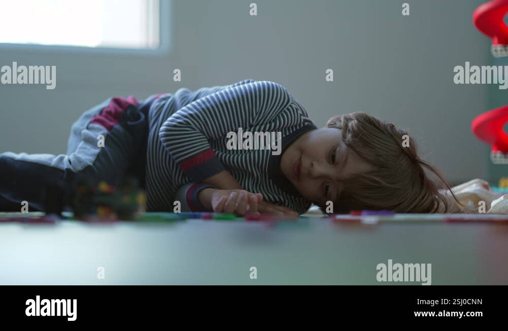Bored small boy laying on floor in bedroom. Kid with nothing to do at ...