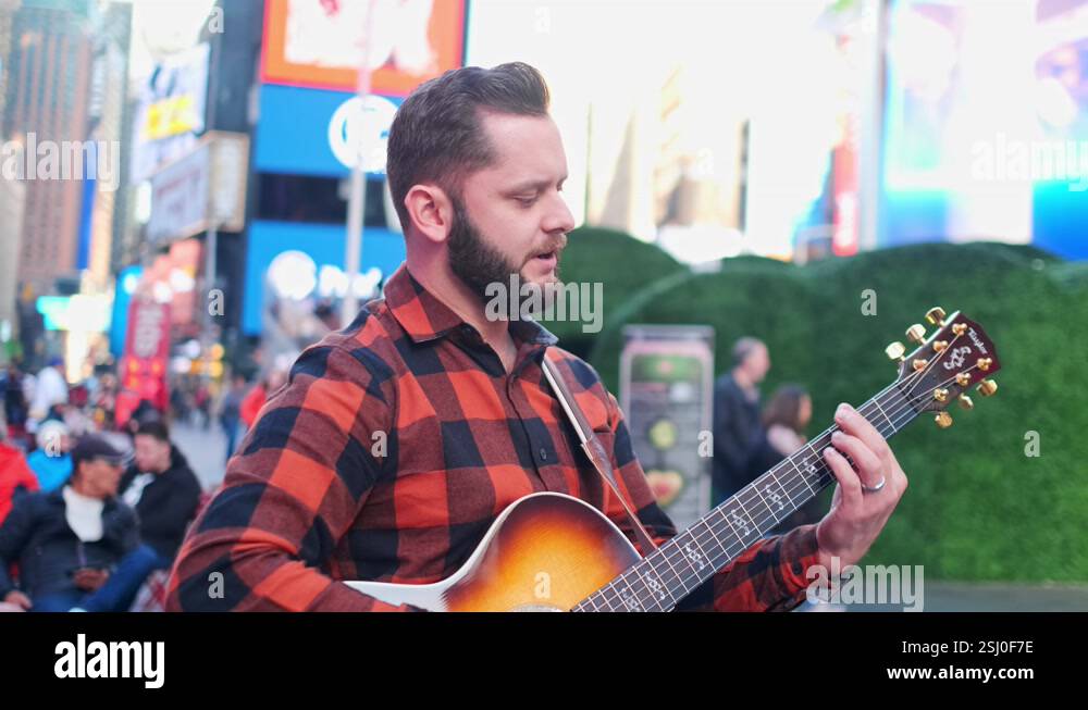 musician is singing in the middle of Times Square and playing a guitar ...