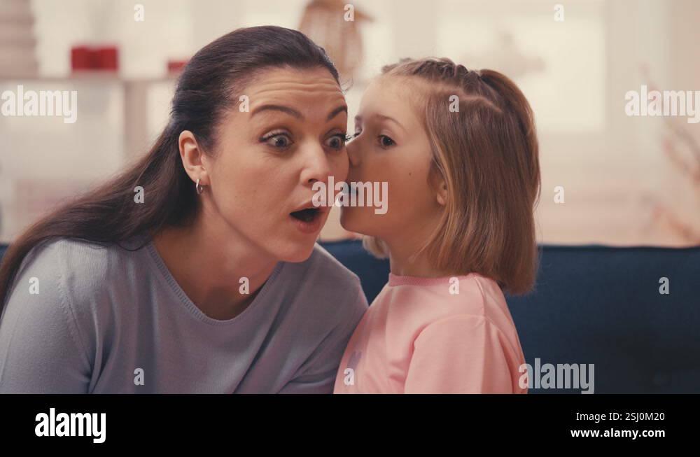 Cute little girl sharing secrets with mother and hugging her, happy ...