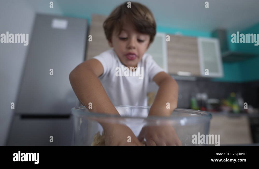 Messy child cooking at home mixing dough with hands. Kid preparing food ...