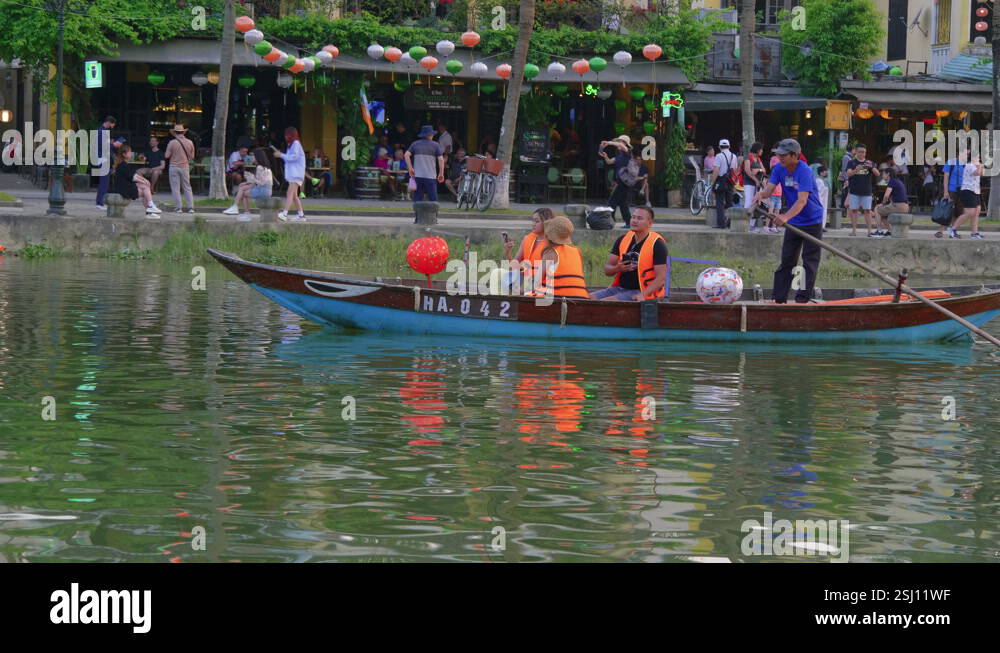 A tracking shot of a lantern boat with tourists onboard along the river ...