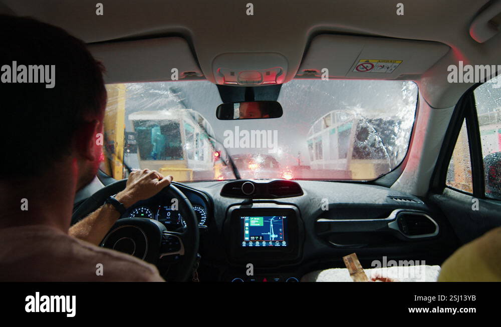 Driving at heavy rain. Man driver sits in the car and waits in a queue ...