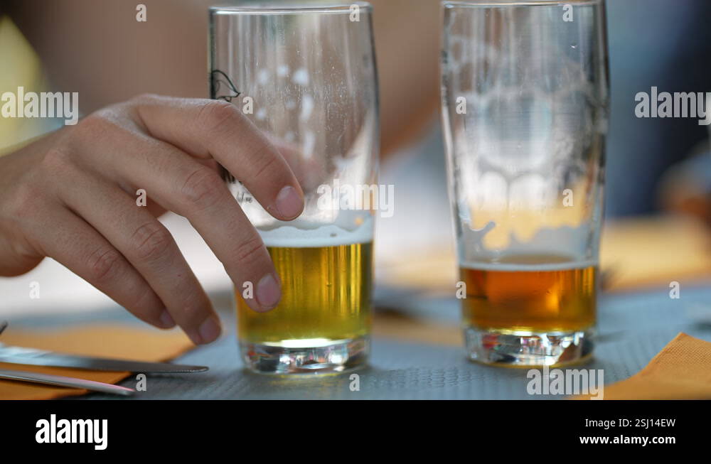 Two half full draft beers at restaurant table. Person hand closeup ...