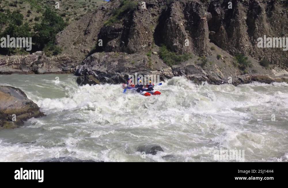 The rafting team descends the rough rapids in the mountain river with ...