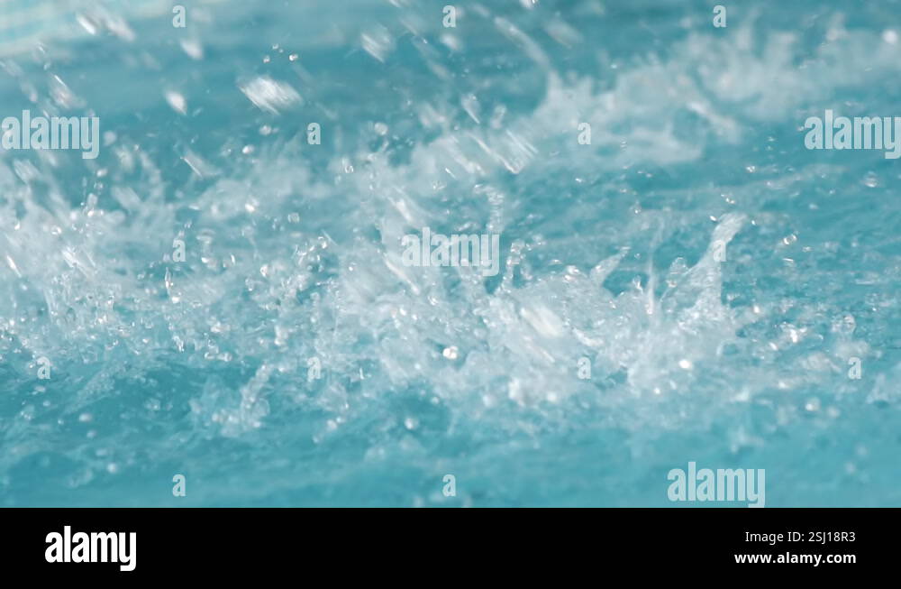Slow motion of water splashing into swimming pool, water drops spraying ...