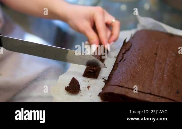 hands cut chocolate cake pudding with nut crumbs into slices. . High ...