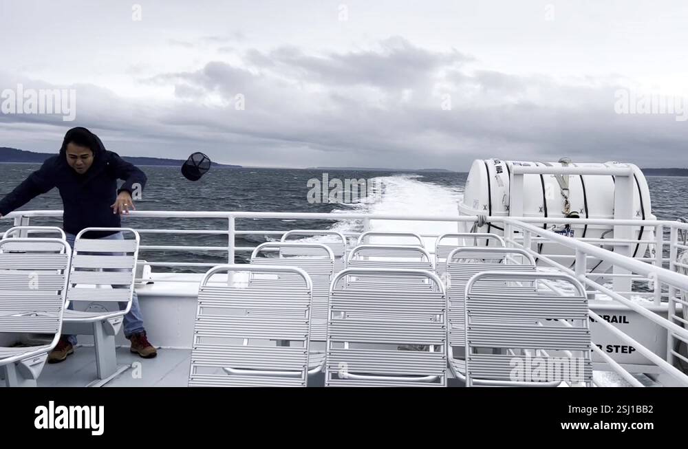 Latin man traveling by boat on the sea. His cap flies with the air ...