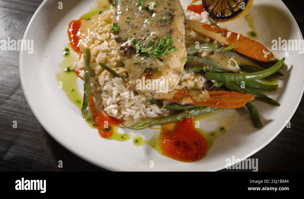Top down view grilled white fish over rice pilaf and roasted vegetables ...