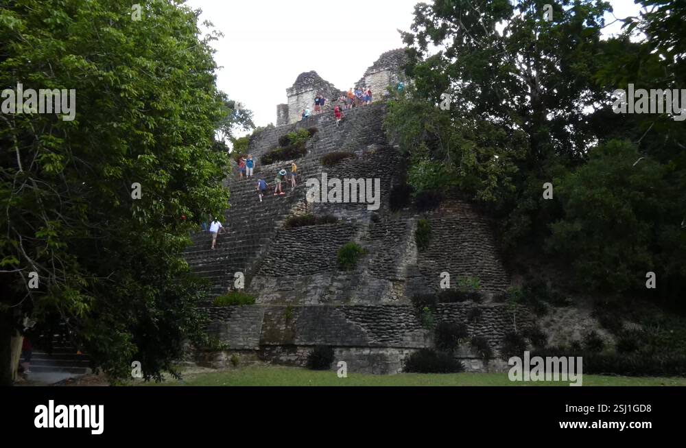 Tourists climbing up on the Temple of the Owl pyramid at Dzibanche ...