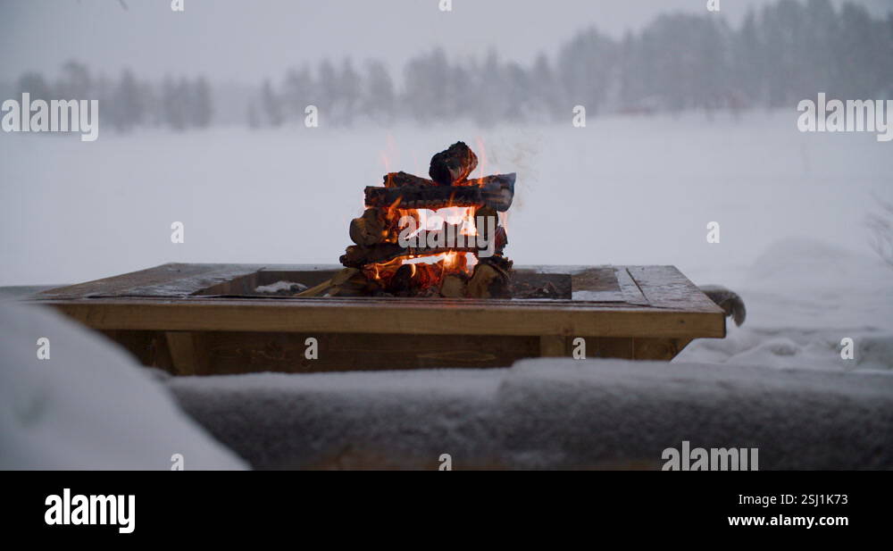 Handheld shot small stack of blazing logs smoking in fire pit in ...