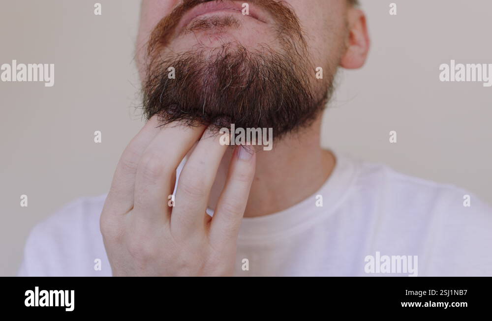 Cropped shot mans hand is unrestrained scratching unshaven chin ...