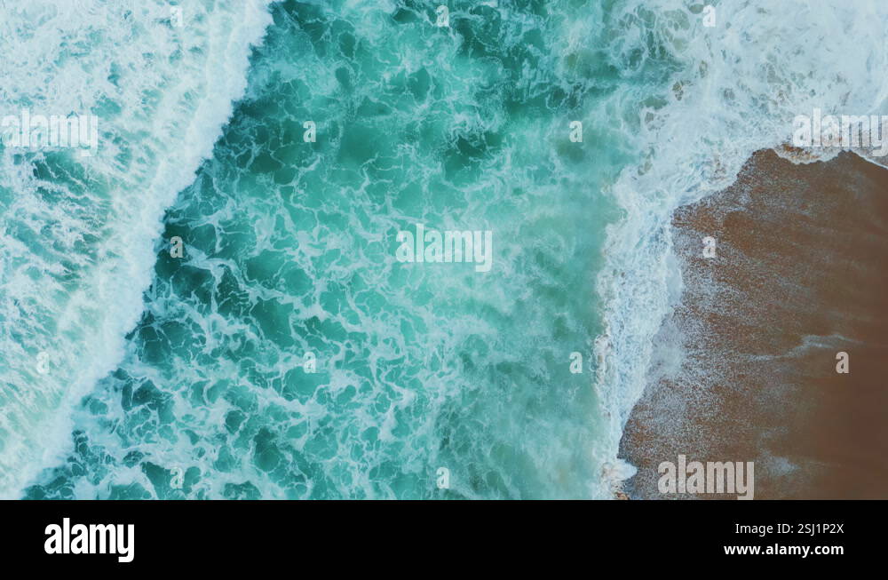 Cinematic aerial ocean scenery foamy waves splashing on sandy beach ...