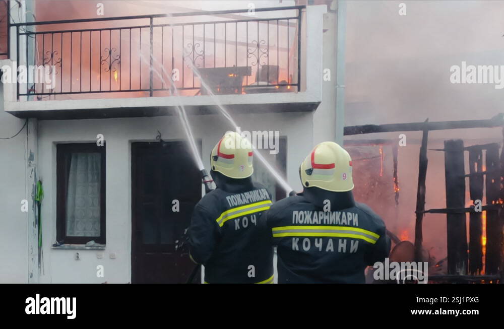 Firefighters spraying water with hose on house burning in flames Stock ...