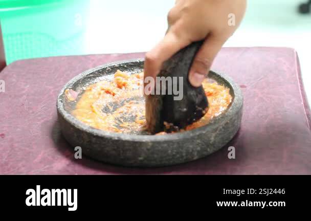 Woman hand grinding spices, shallots, garlic, chilies and salt in a ...