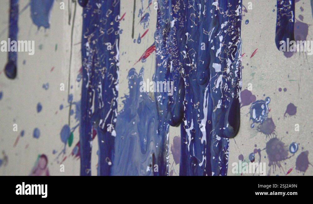 Close up footage of globs of blue paint that is slowly running down a ...