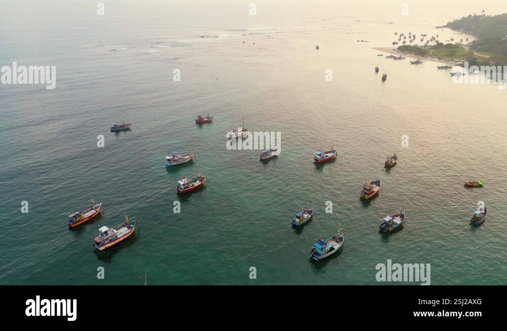 aerial view of many fishing boats berthed in the sea at a golden sunset ...