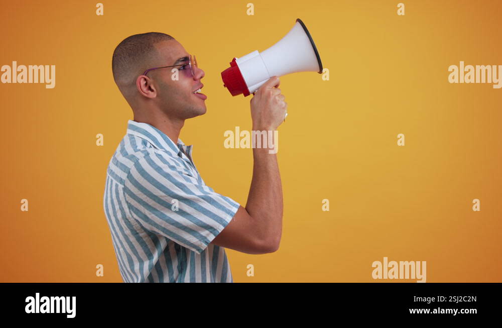 Young Black male announcer covering his face with bullhorn over orange ...
