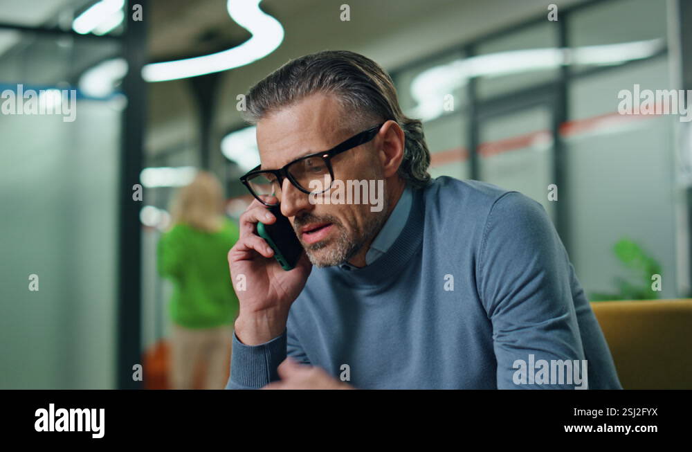 Angry businessman arguing smartphone call indoors. Nervous man speaking ...