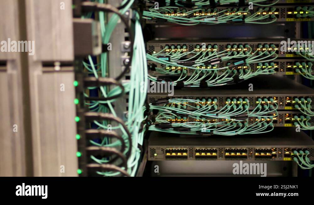 Green wires plugged in to servers and storage in a data center, server ...