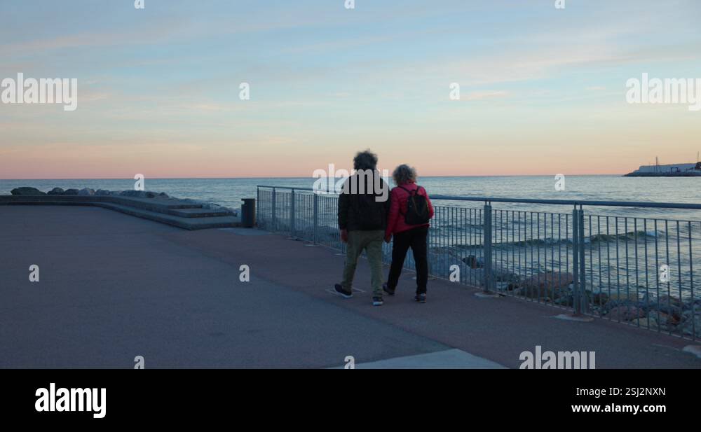 Romantic couple strolls on pier at sunset next to the sea Stock Video ...