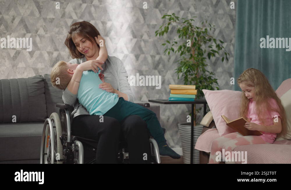 Loving mother hugs and kisses toddler while daughter reading Stock ...