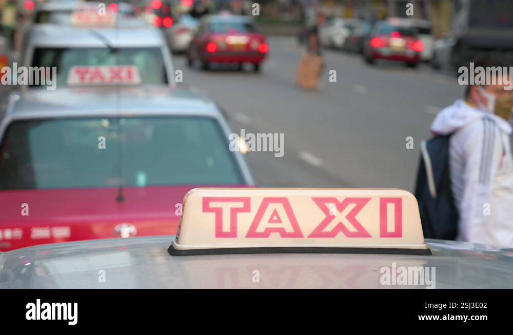 A line of taxi cabs and lit signs sitting on the hood seen stationed in ...