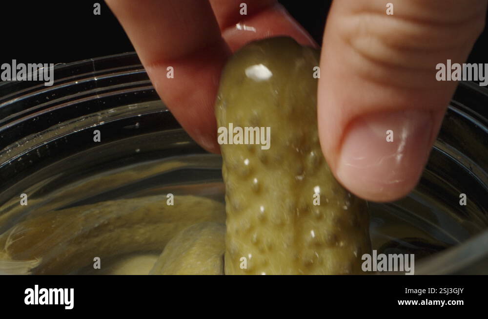 I take out a pickle from a jar on a black background. Dolly slider ...