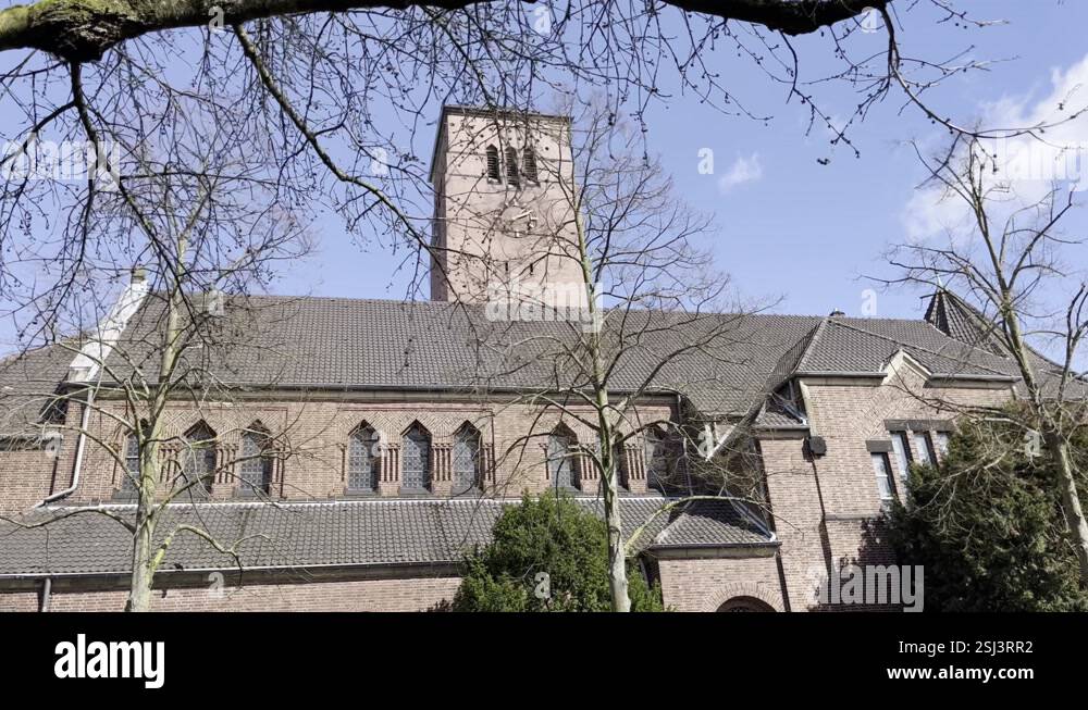 old big brick church with big clock on the tower behind old trees Stock ...