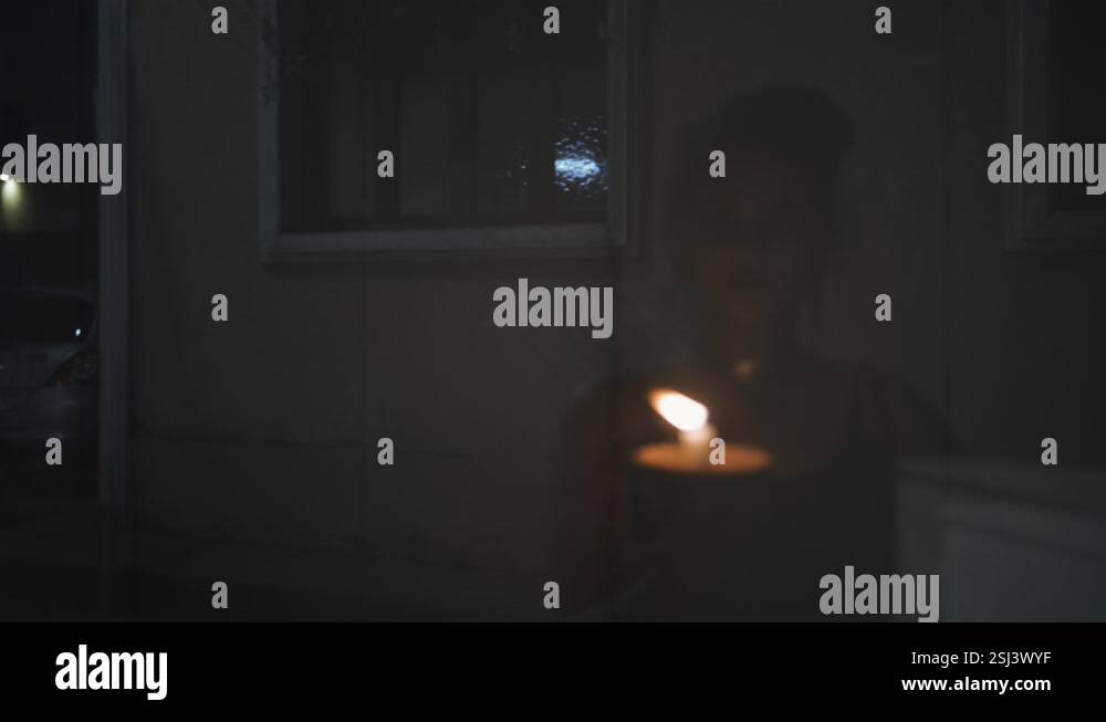 Pretty woman holding a lit candle flame in a glass reflection ...