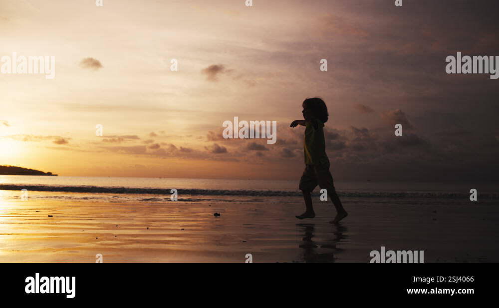Boy run on the beach at sunset, spreading hands like bird wings imagine ...