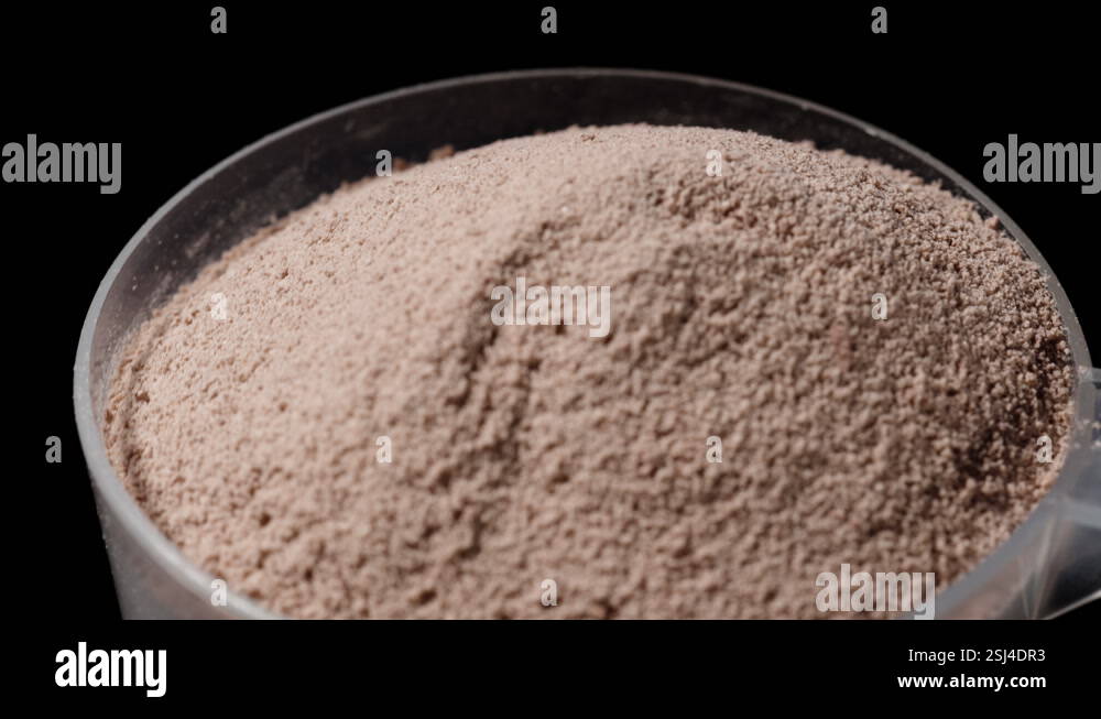 Protein powder in a measuring spoon. it rotates on a black background ...