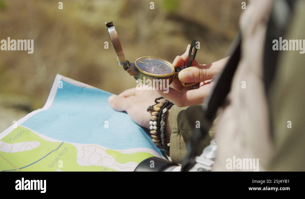 Close up of Sunlit Map and Compass in Hands Of Two Young Women ...