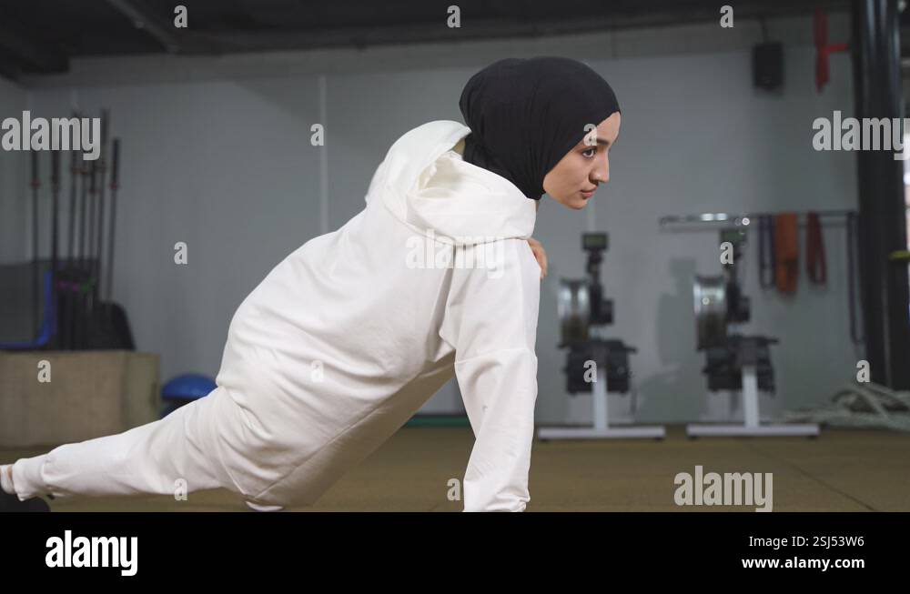 Arab woman and sport. A woman in a hijab for sports is doing push-ups ...