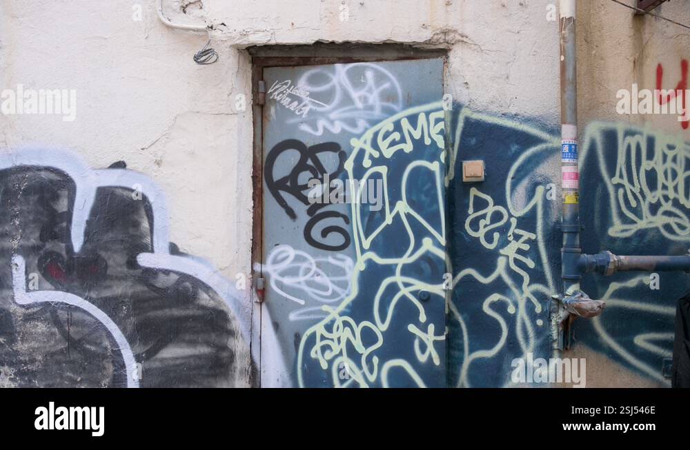 A wall, pipe, and building door located at the back street alley is ...