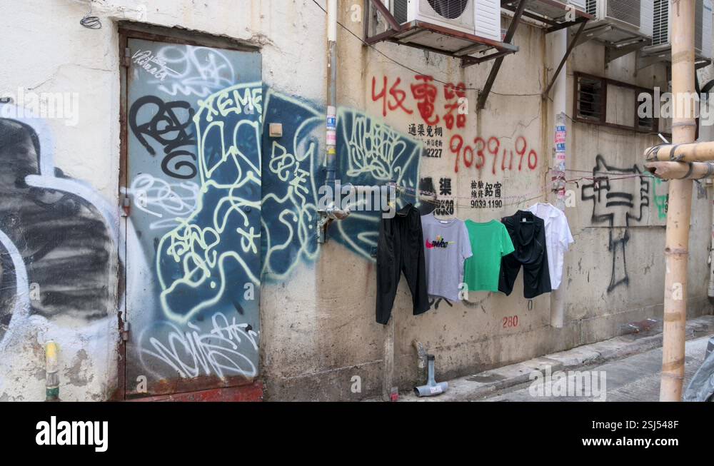 A laundry hanging at a back street alley dries next to a wall, pipe ...