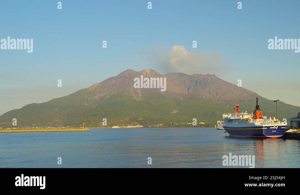 Active Sakurajima volcano billowing smoke, boats at sea; time lapse ...