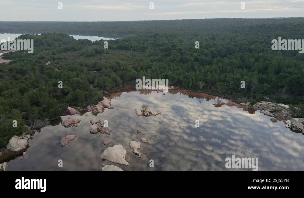 Parallax of clouds against the reflection across the lake seen by drone ...