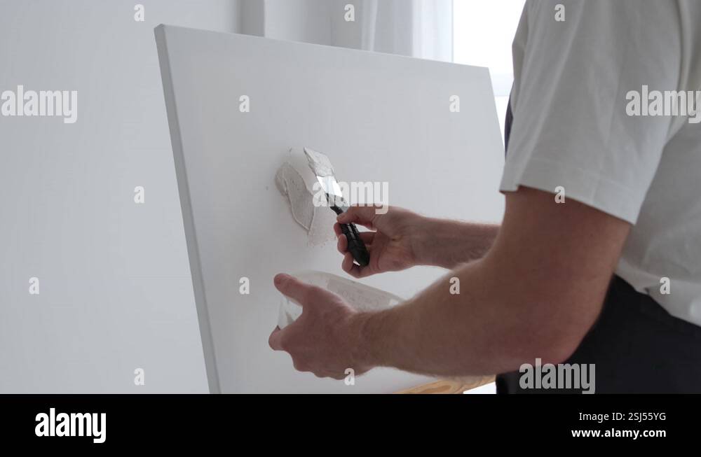 The artist creates a picture on a white canvas using plaster. Creating ...