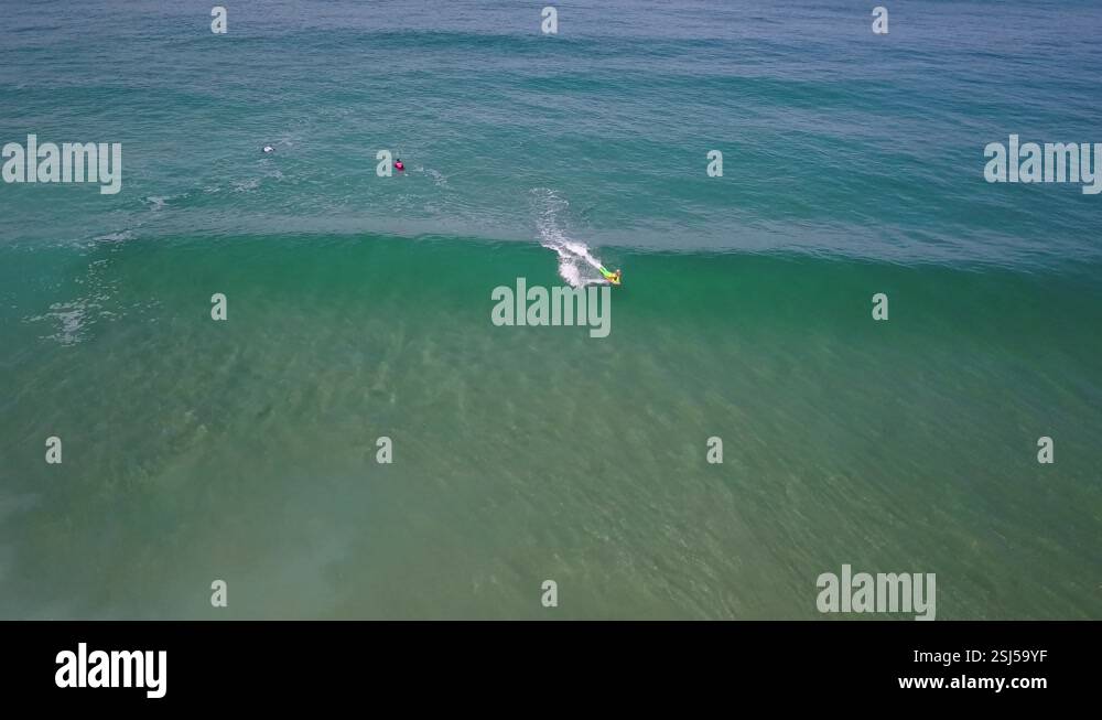 Bodyboarder in yellow wetsuit takes off on clean wave in green ocean ...