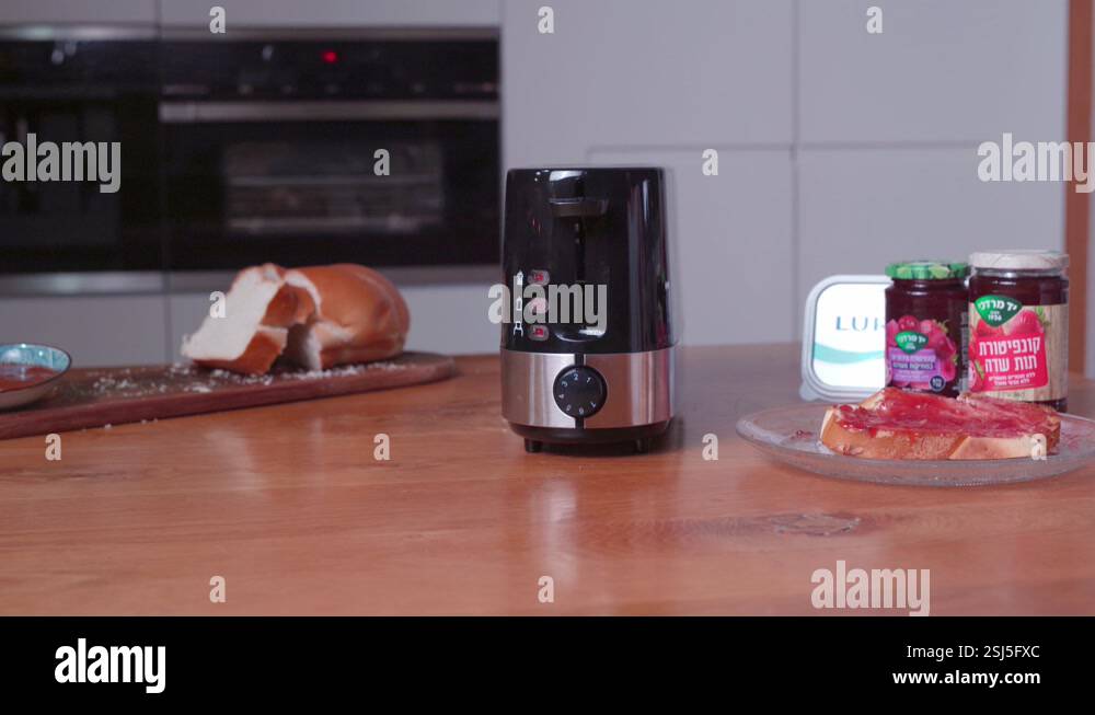 Toast with jelly is served on countertop in modern kitchen, tilting up ...