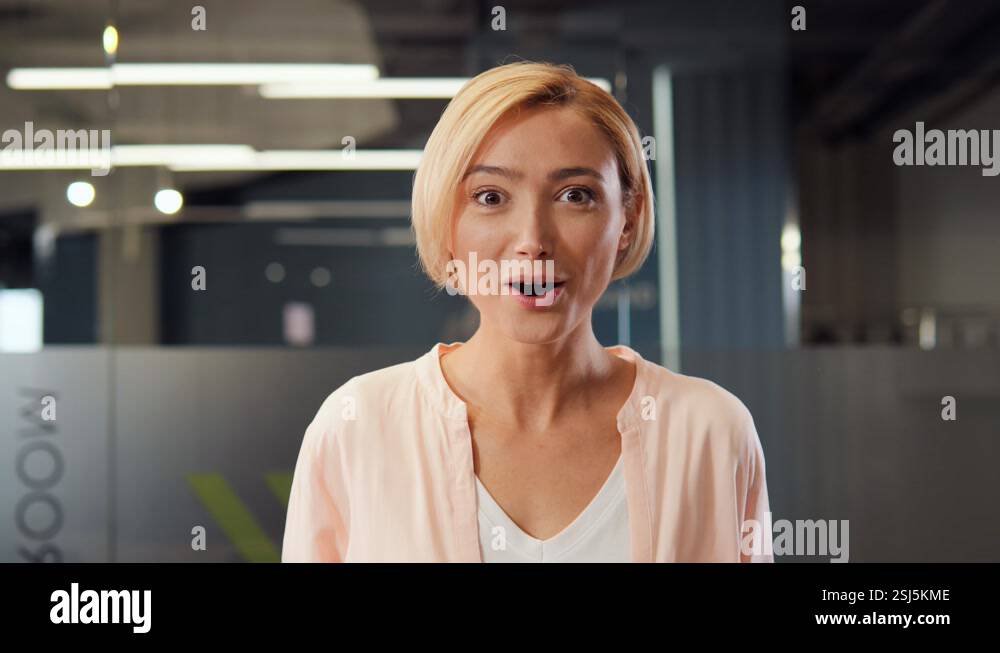 Extited blonde woman looking surprised, impressed, smiling happily ...