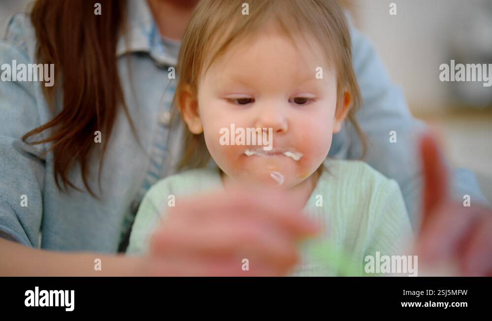 Mom feeding her baby with milk porridge at home. Portrait of baby ...