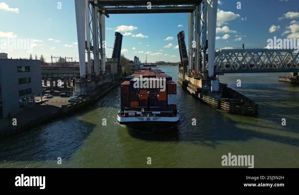 Big heavy loaded container ship passing the open drawbridge on a sunny ...