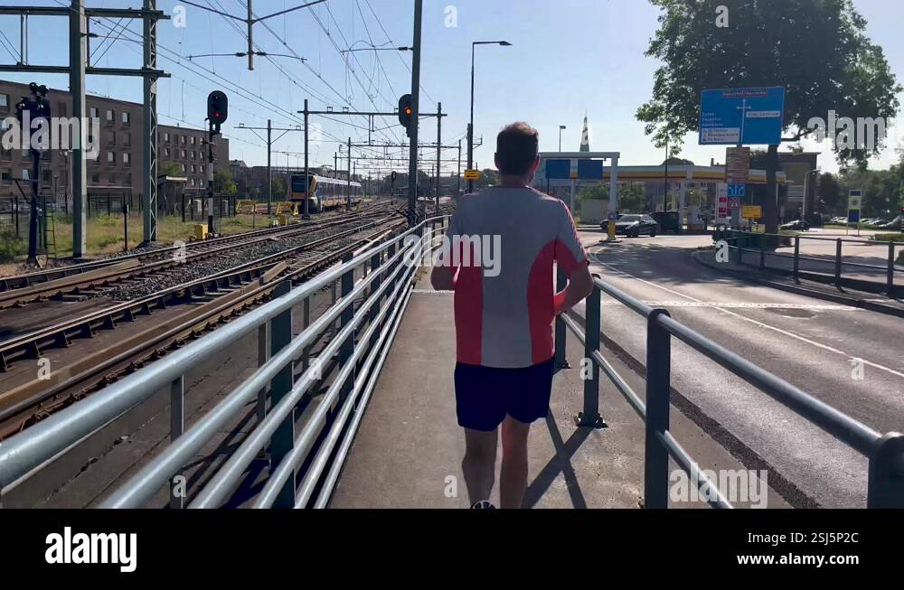 Following fast running male on steel bridge and along train tracks ...